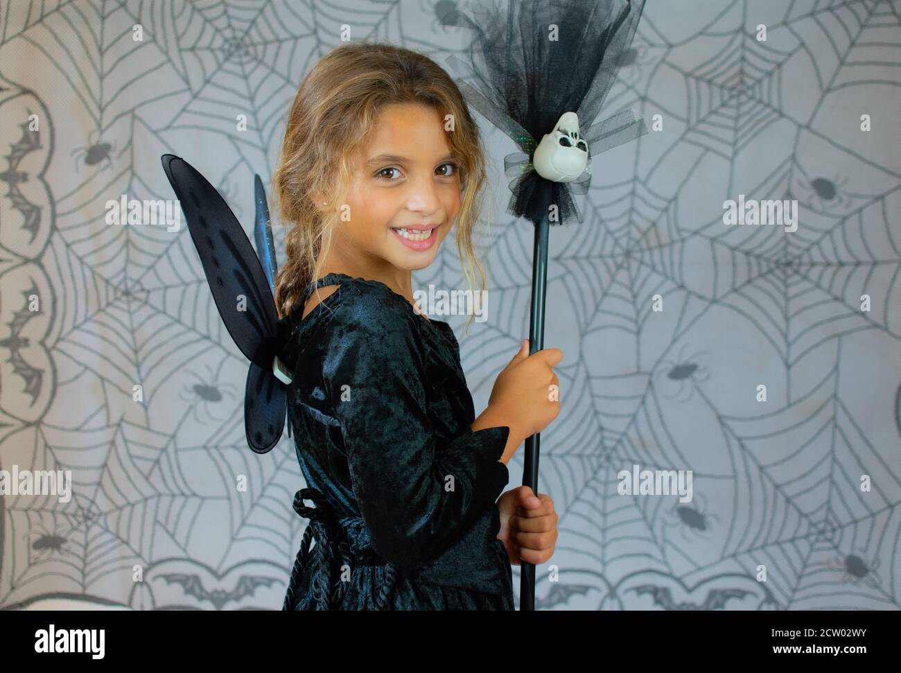 funny child girl in witch costume for Halloween over cobweb background ...