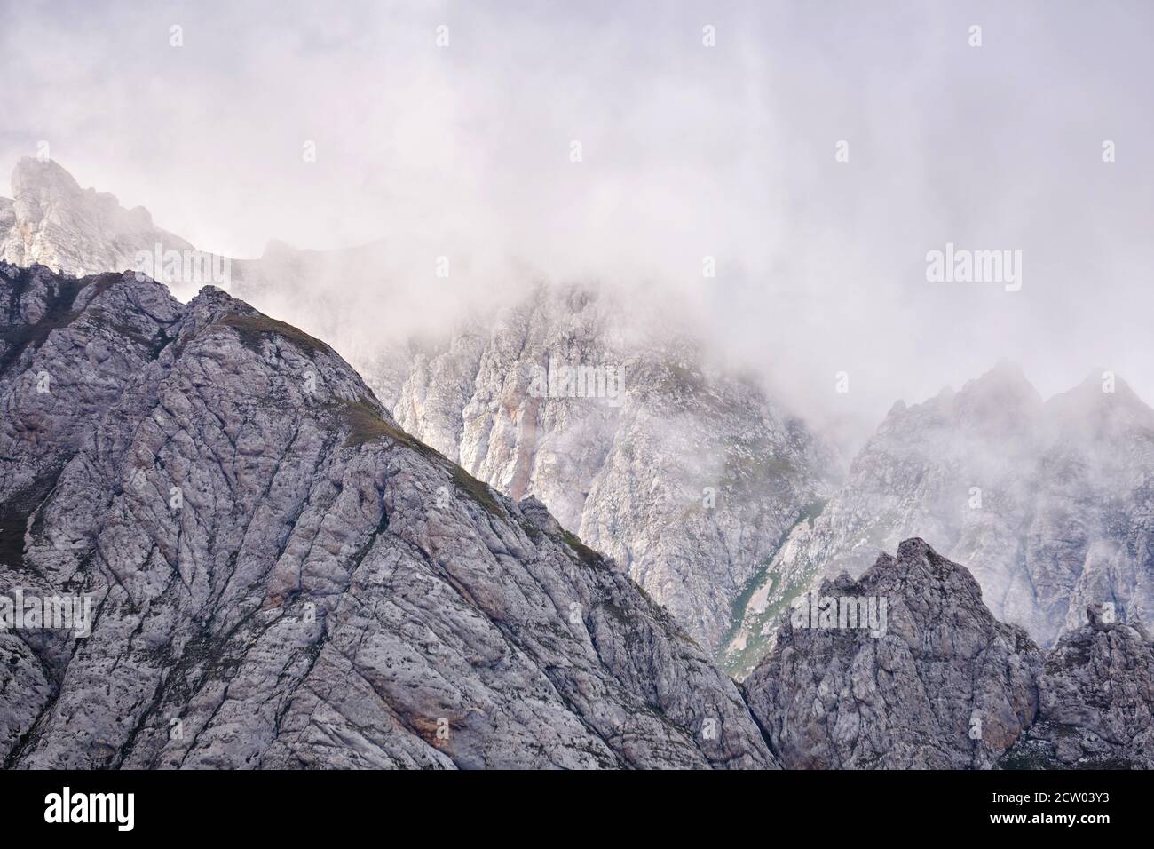 alpine landscape - sharp rocky mountain peaks hide in the clouds Stock ...