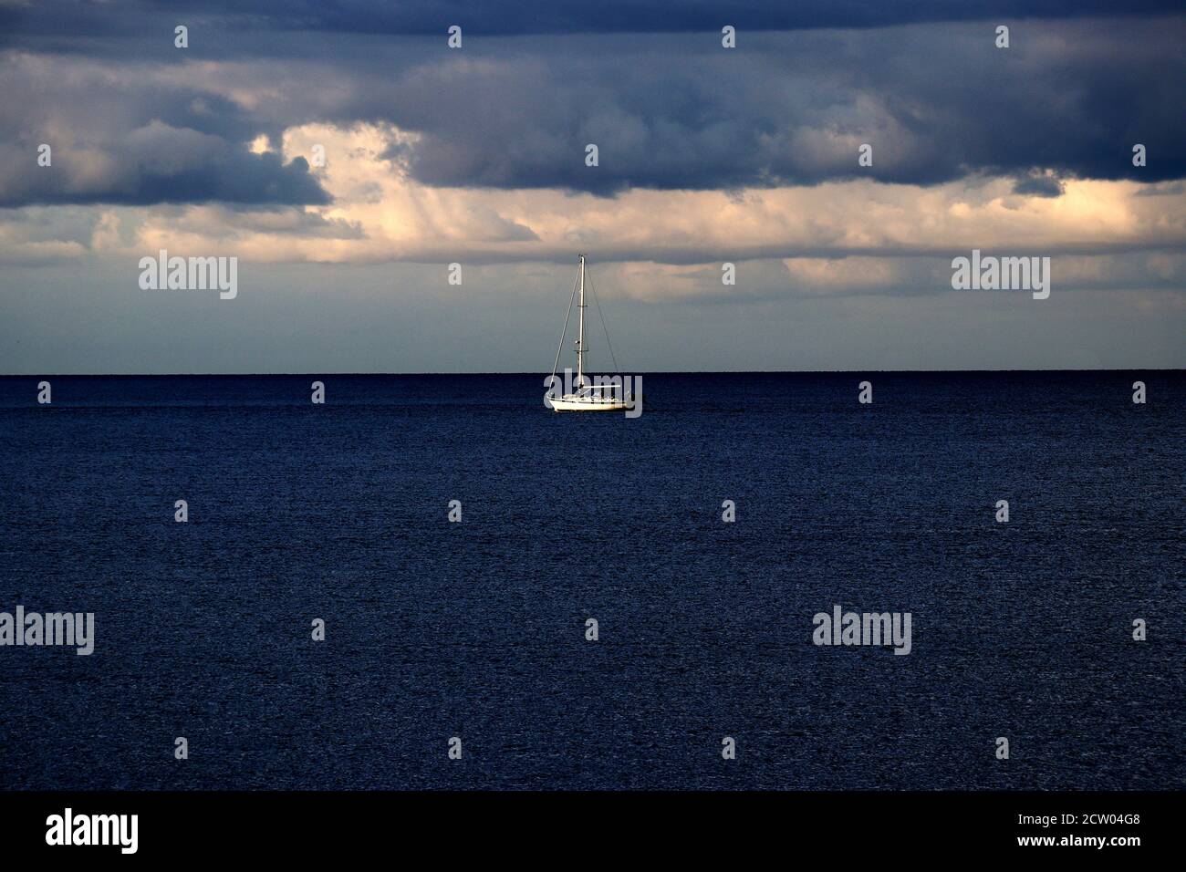 Sailboat sailing on an empty and dark blue sea - background Stock Photo ...