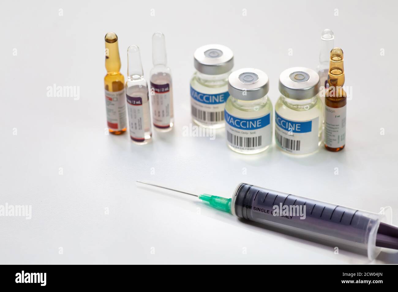 Hypodermic syringe needle with vaccine bottles and injection vials on ...