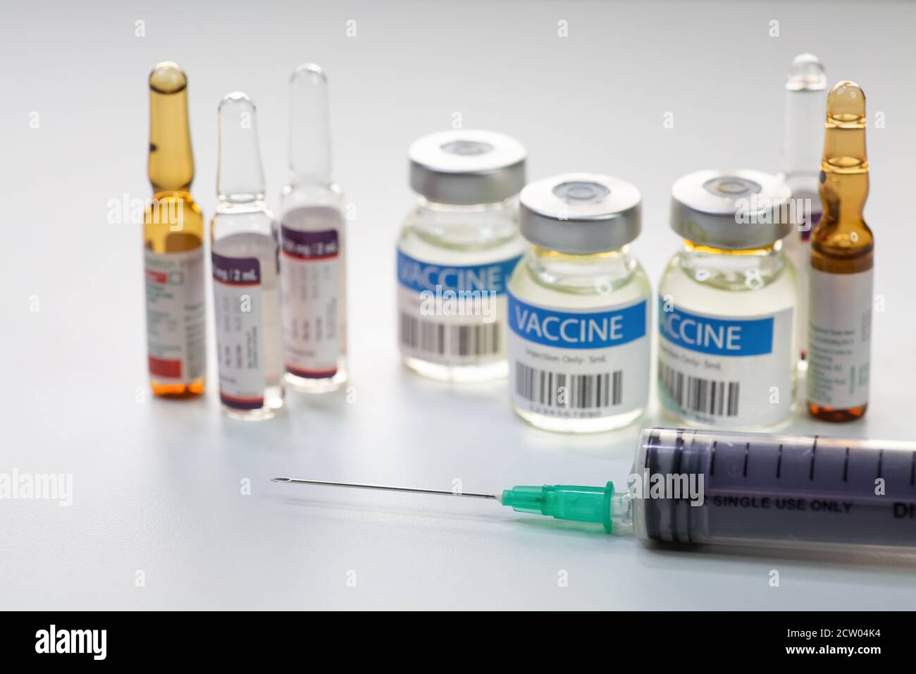 Hypodermic syringe needle with vaccine bottles and injection vials on ...
