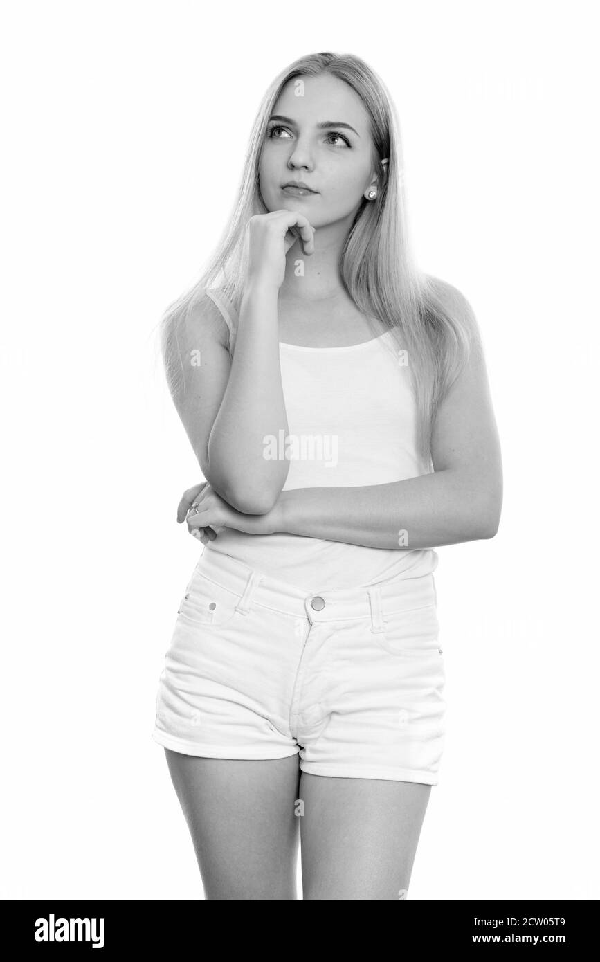 Studio shot of young beautiful teenage girl standing while thinking ...