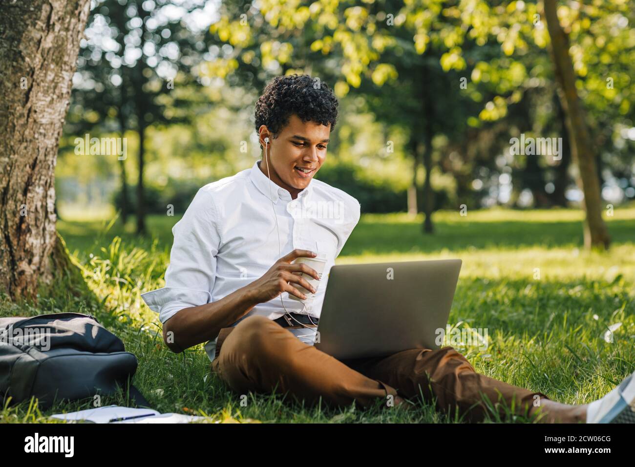 Smiling african american college boy using a laptop computer sitting in ...