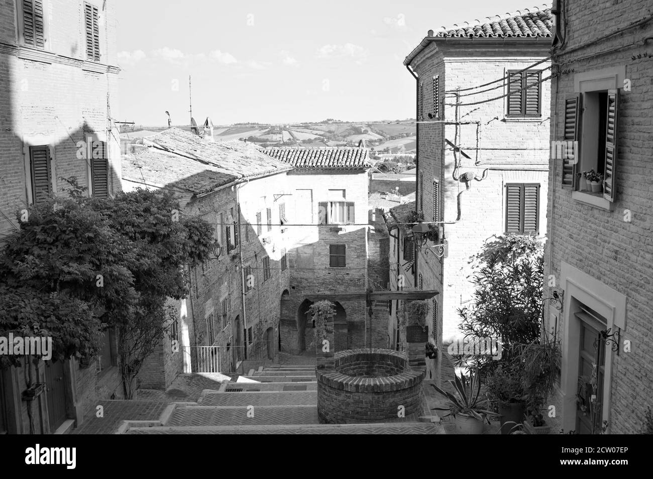 A stairway in a medieval Italian village with an old brick well ...