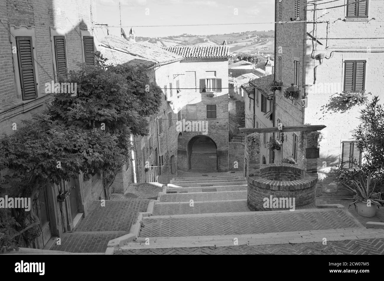 A stairway in a medieval Italian village with an old brick well ...