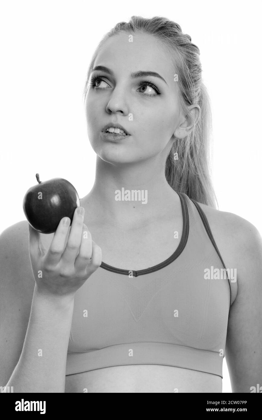 Face of young beautiful teenage girl holding apple while thinking ready ...