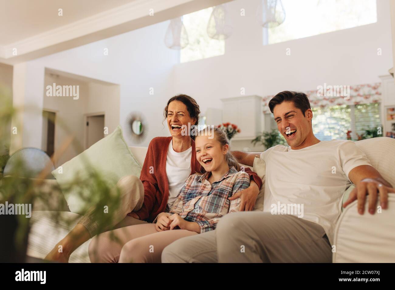 Father, mother and daughter watching tv and laughing together. Family ...