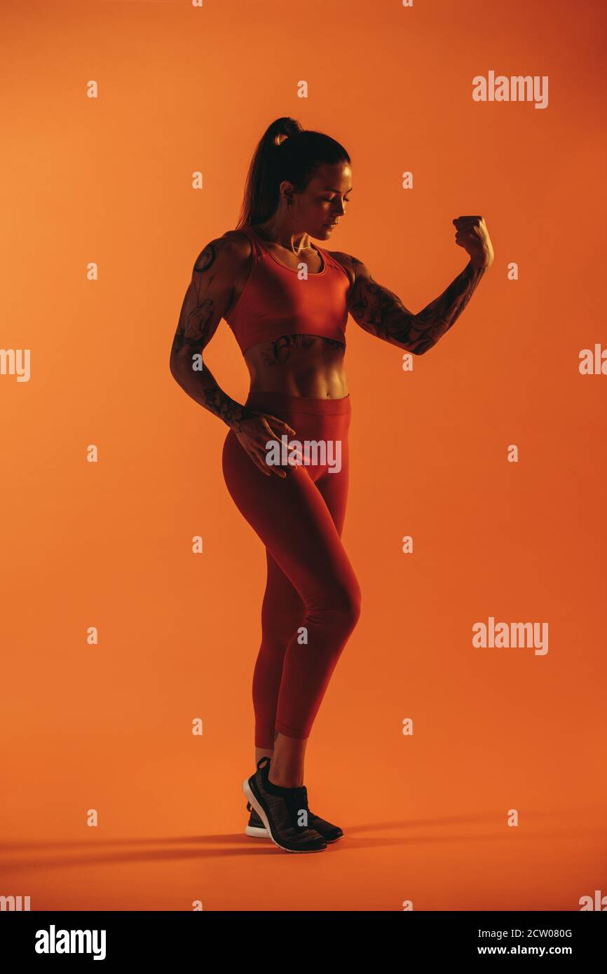Monochrome portrait of female body building athlete on orange ...