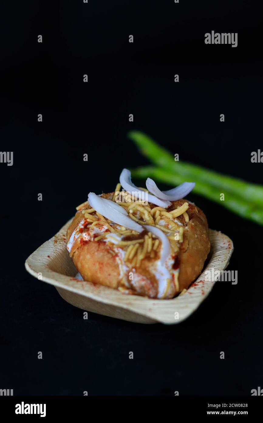 Indian fried chat kachori topped with curd and sev and onions on a ...