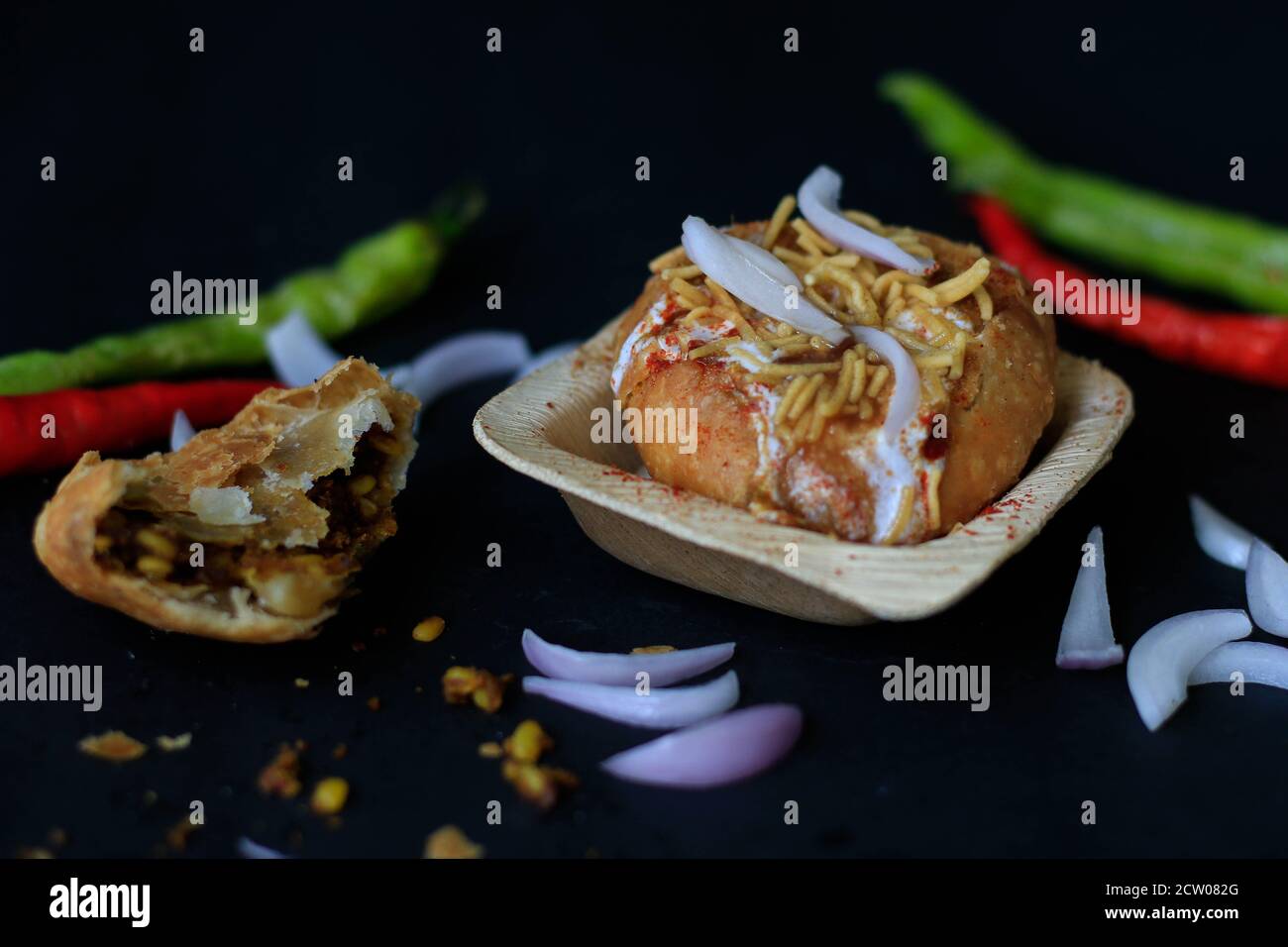 Indian fried chat kachori topped with curd and sev and onions on a ...