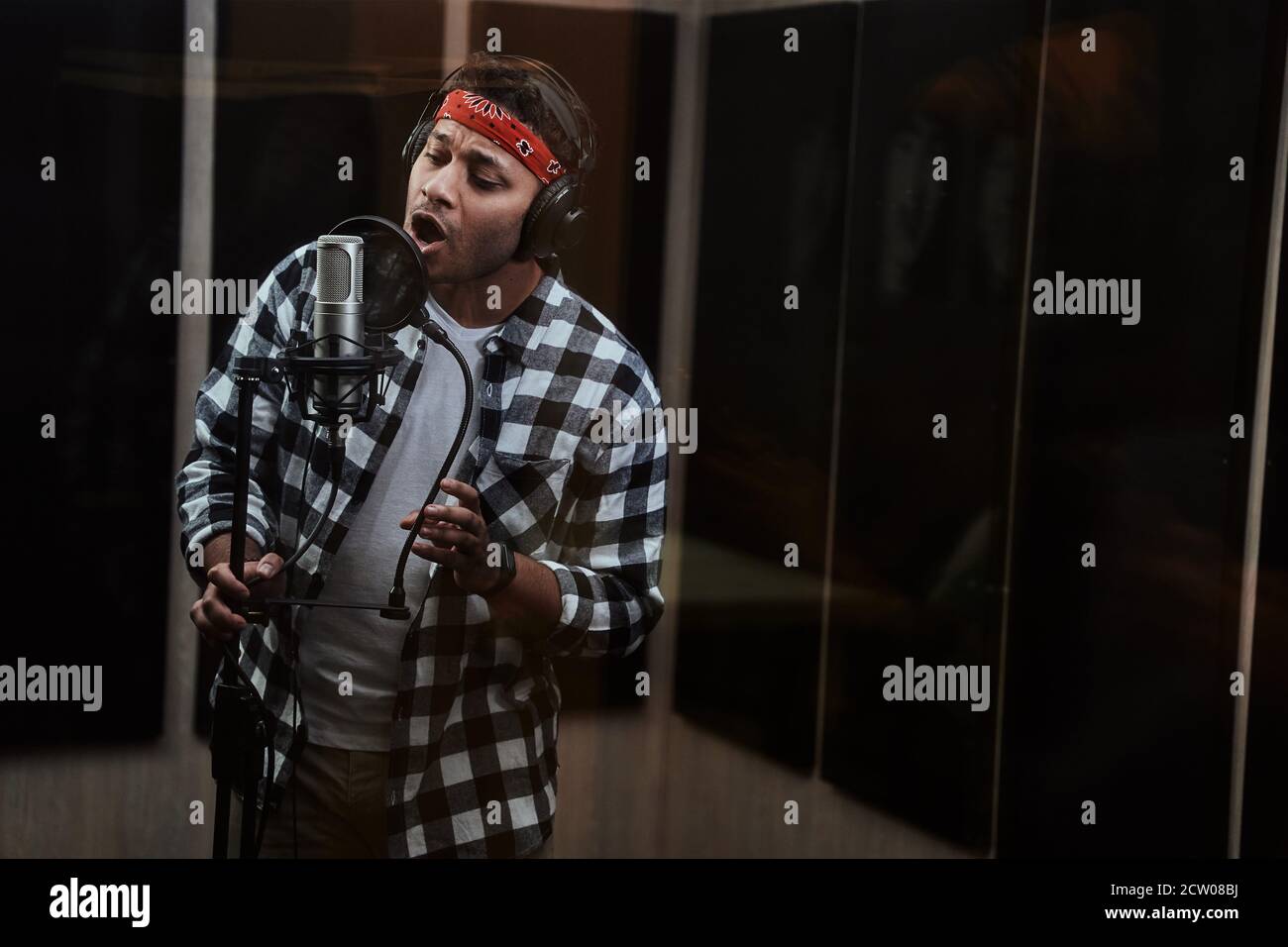 Portrait of young man, male artist looking focused, singing into a ...