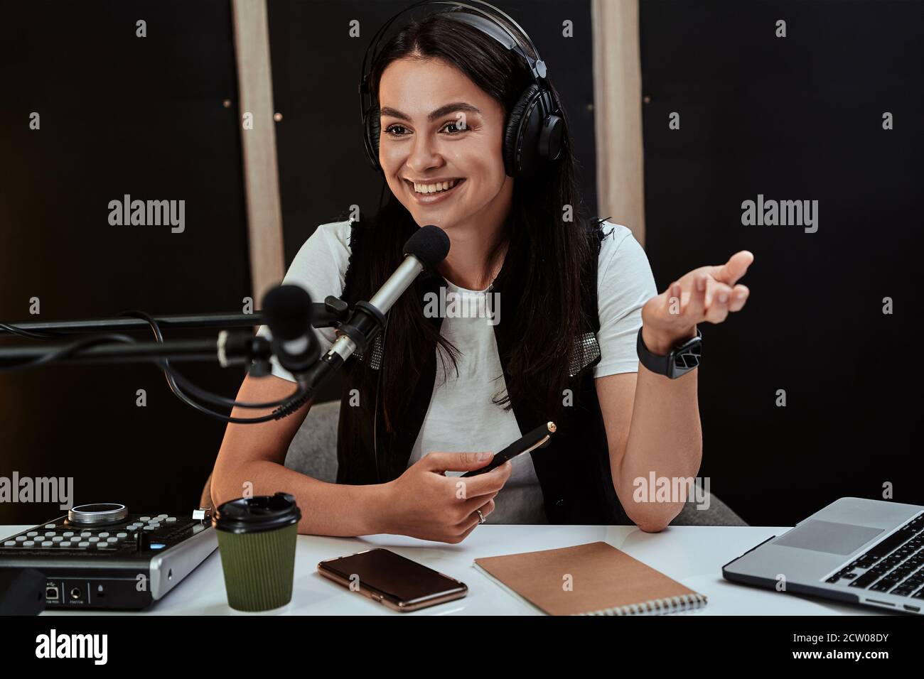 Portait of attractive young female radio host looking emotional while ...