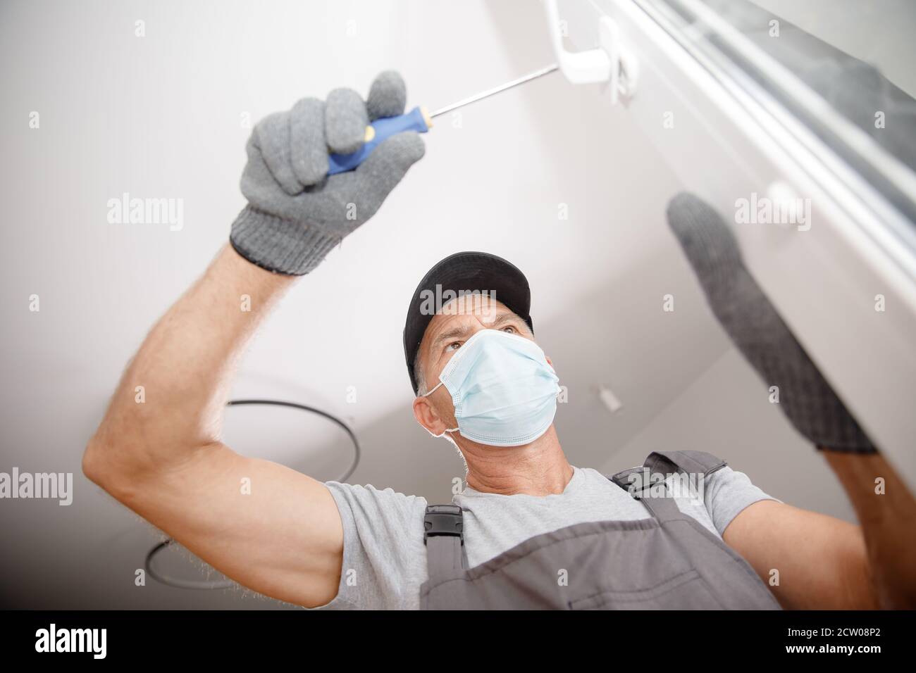 Worker man installs plastic windows and doors with double-glazed white ...