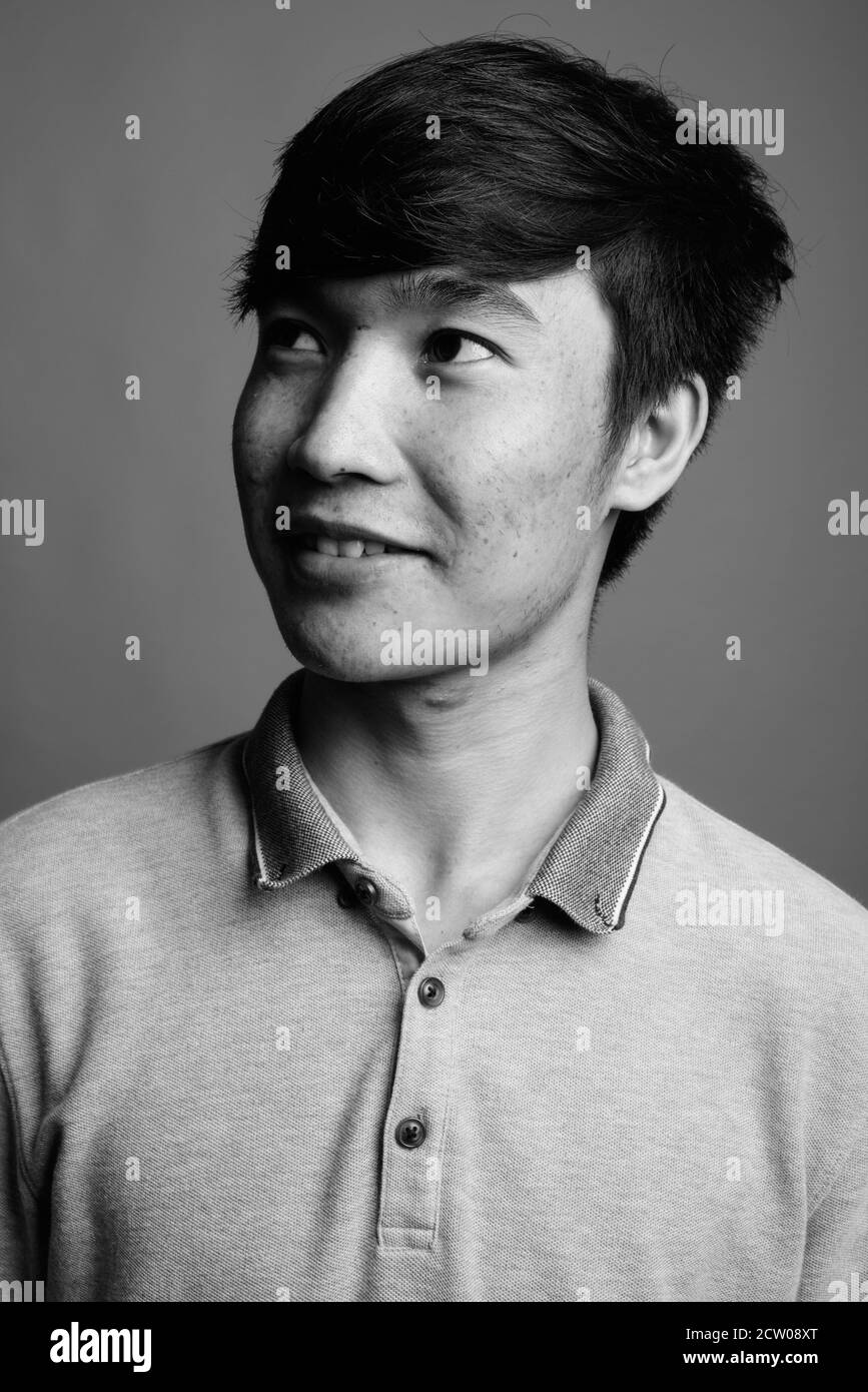 Young Asian man wearing gray polo shirt against gray background Stock ...