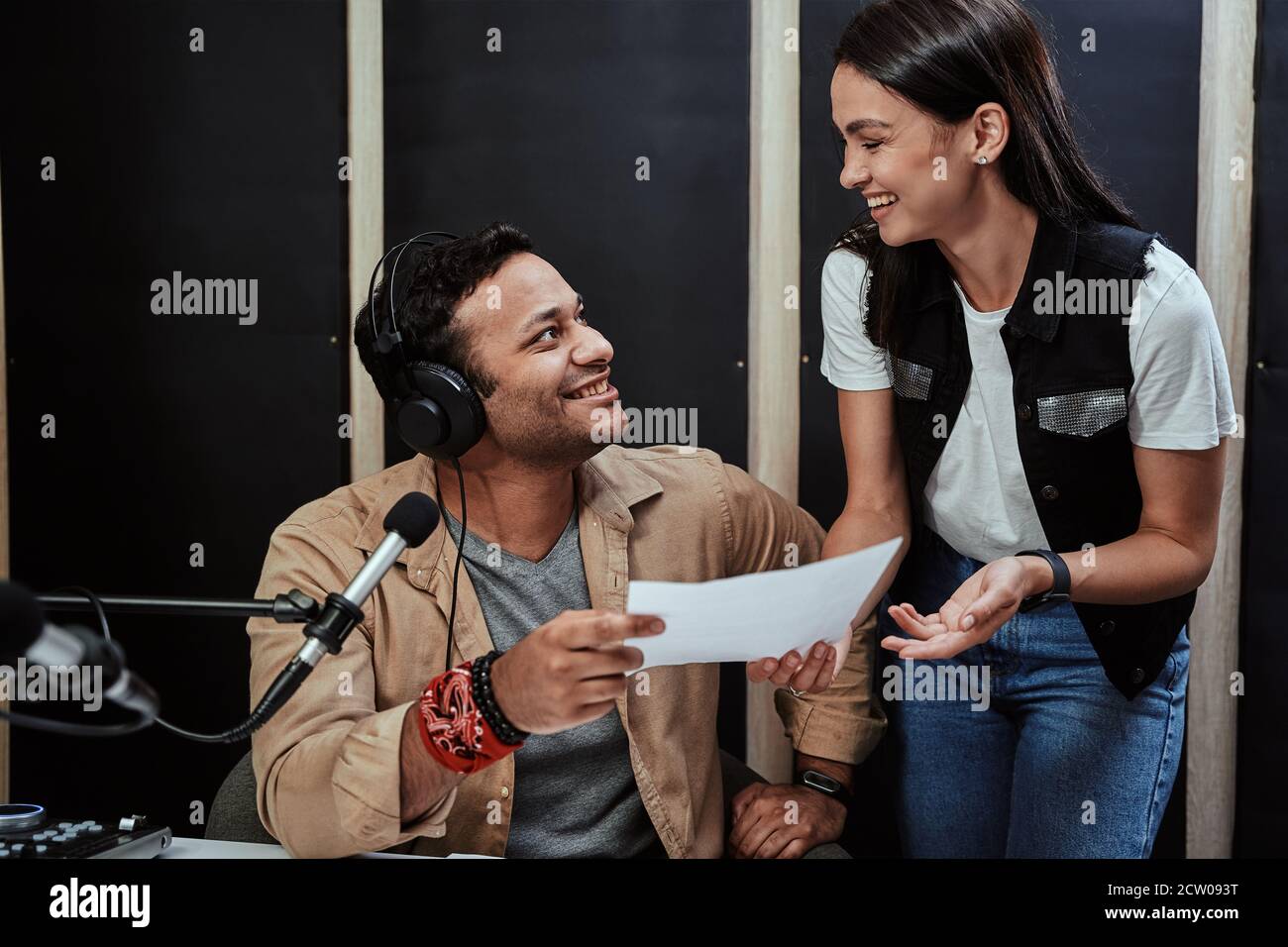 Portrait of young male radio host looking at his female colleague while ...