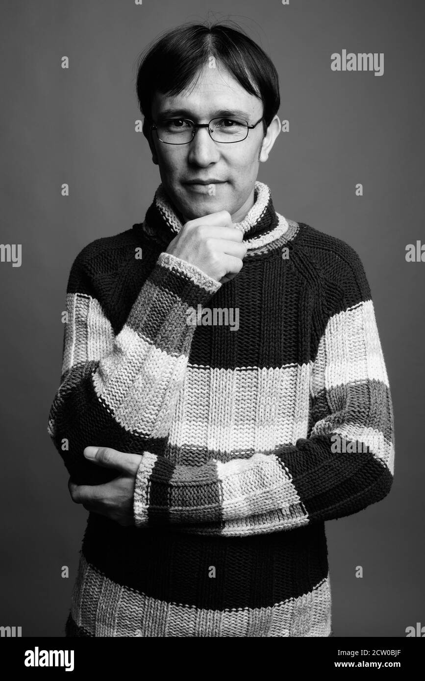 Young Asian nerd man wearing turtleneck sweater against gray background ...
