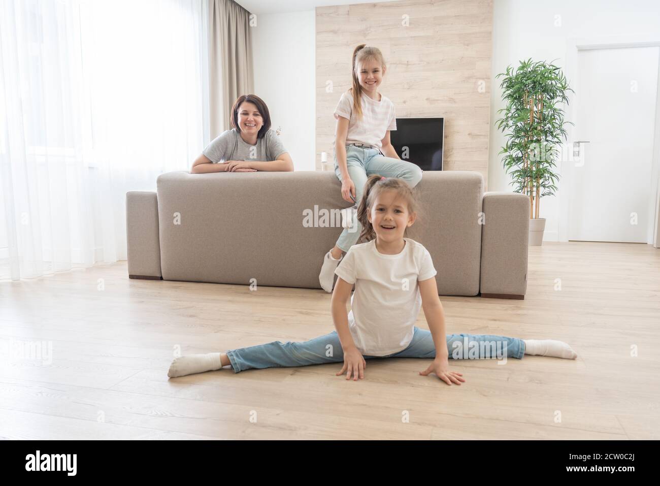 Mother and two daughters having fun in living room at home. Happy family and single mother ...