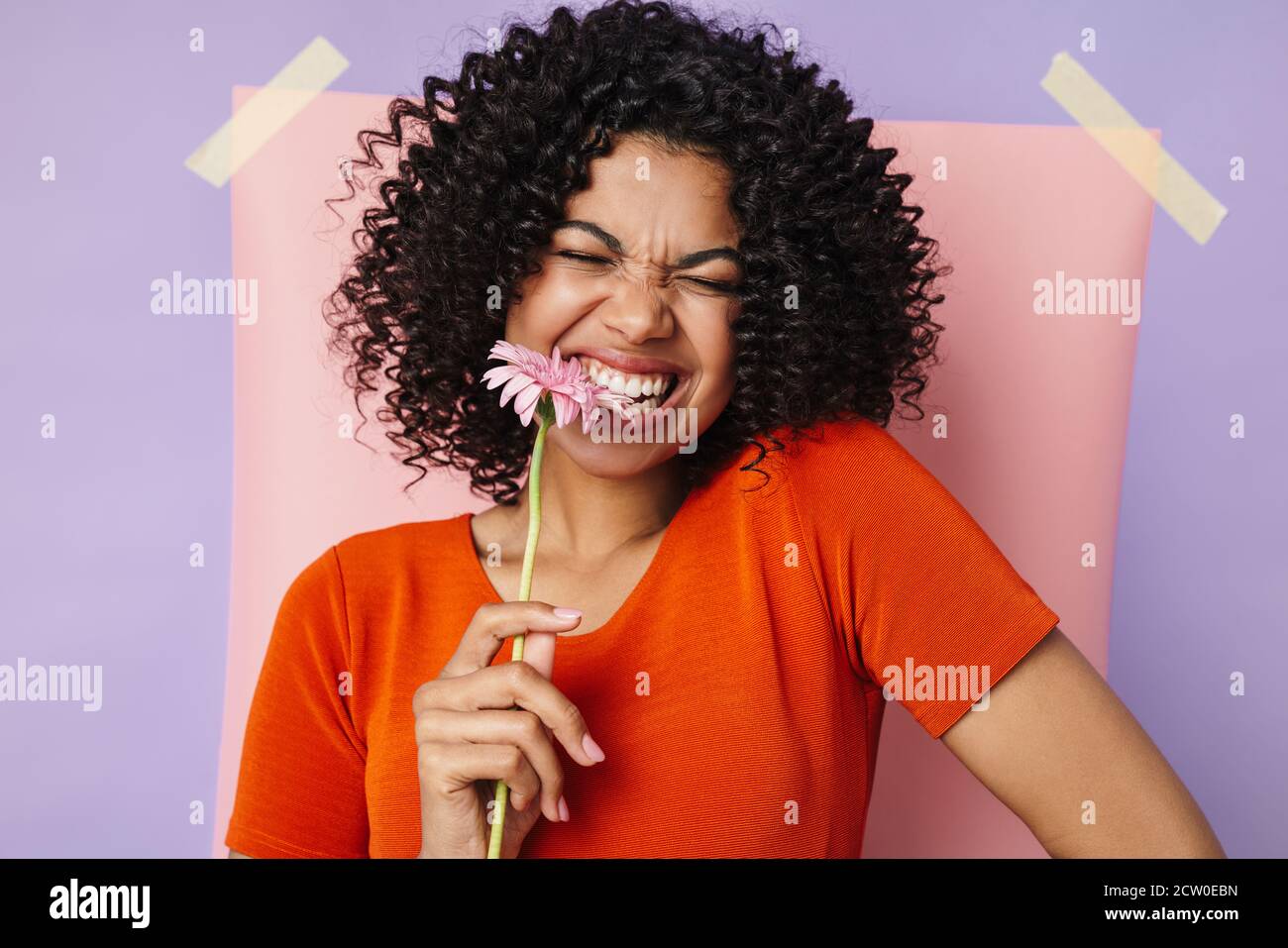 Image of cheerful african american woman smiling while biting flower ...