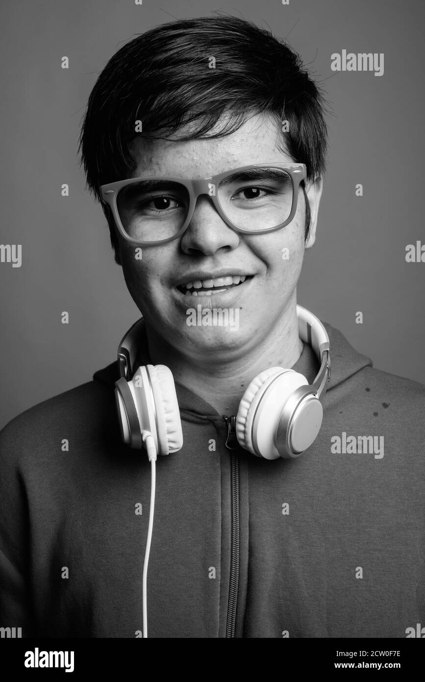 Young Asian teenage boy wearing headphones against gray background ...