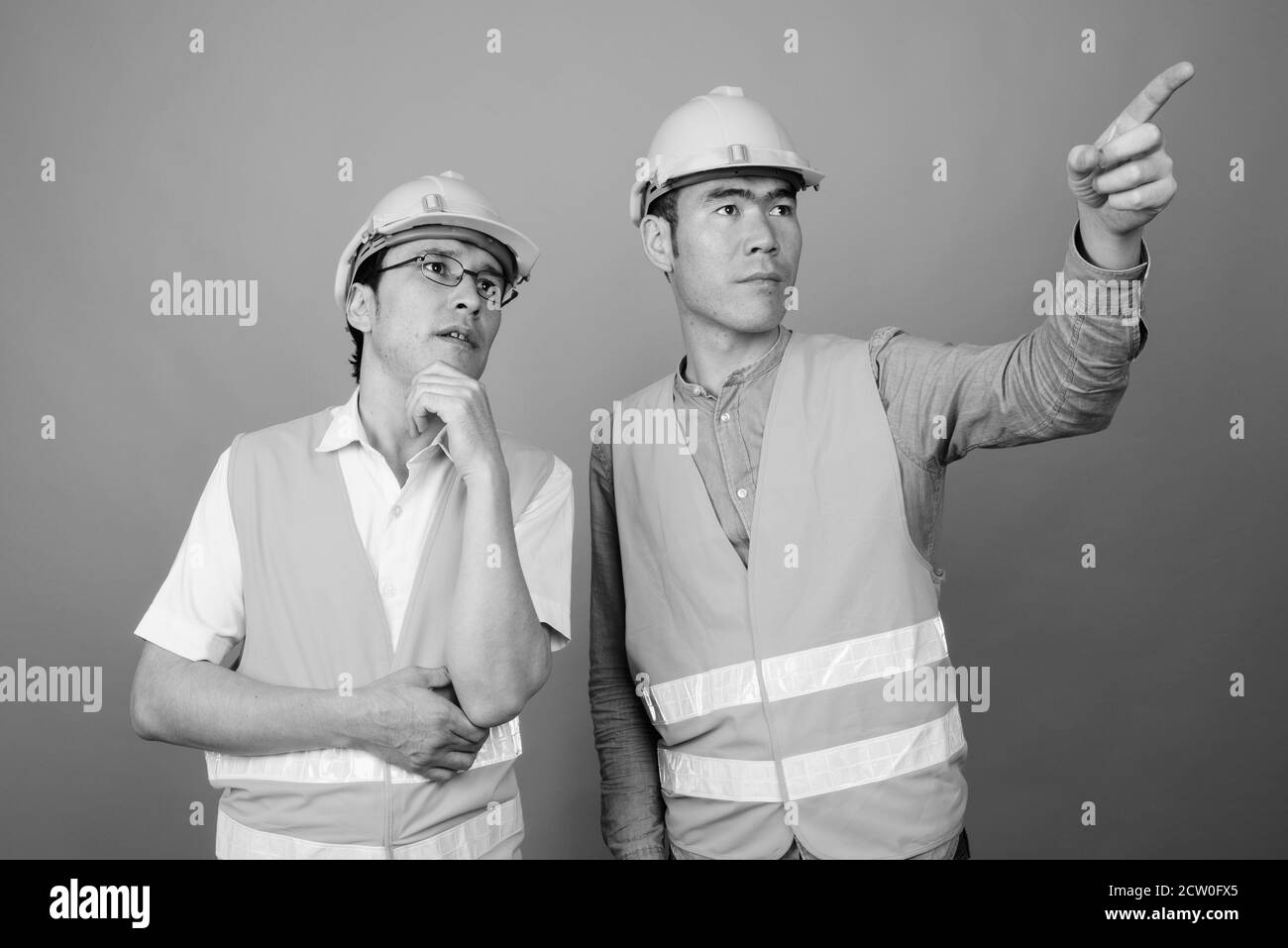 Two young Asian men construction worker together against gray ...