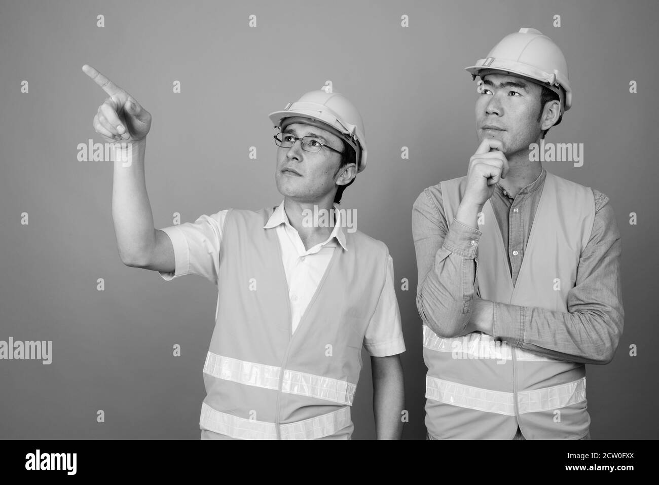 Two young Asian men construction worker together against gray ...