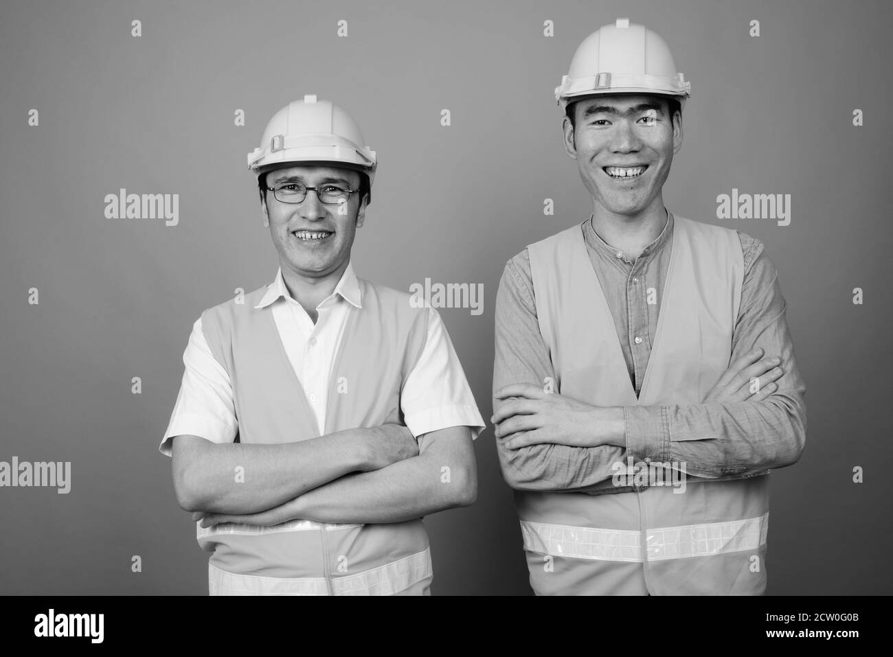 Two young Asian men construction worker together against gray ...