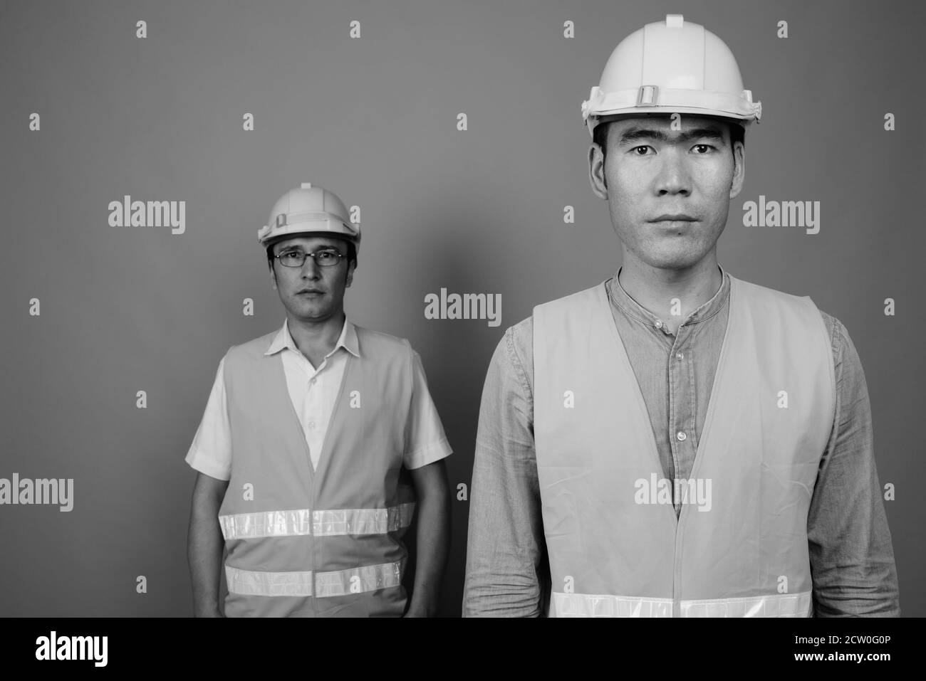 Two young Asian men construction worker together against gray ...