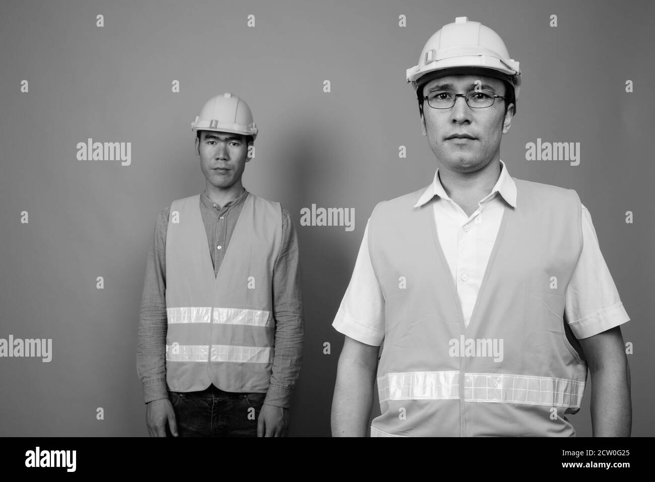 Two young Asian men construction worker together against gray ...