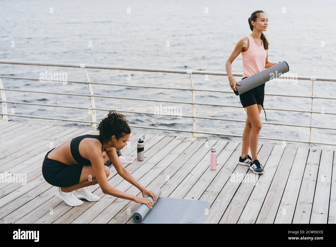 Image of focused multinational sportswomen working out on mats at ...