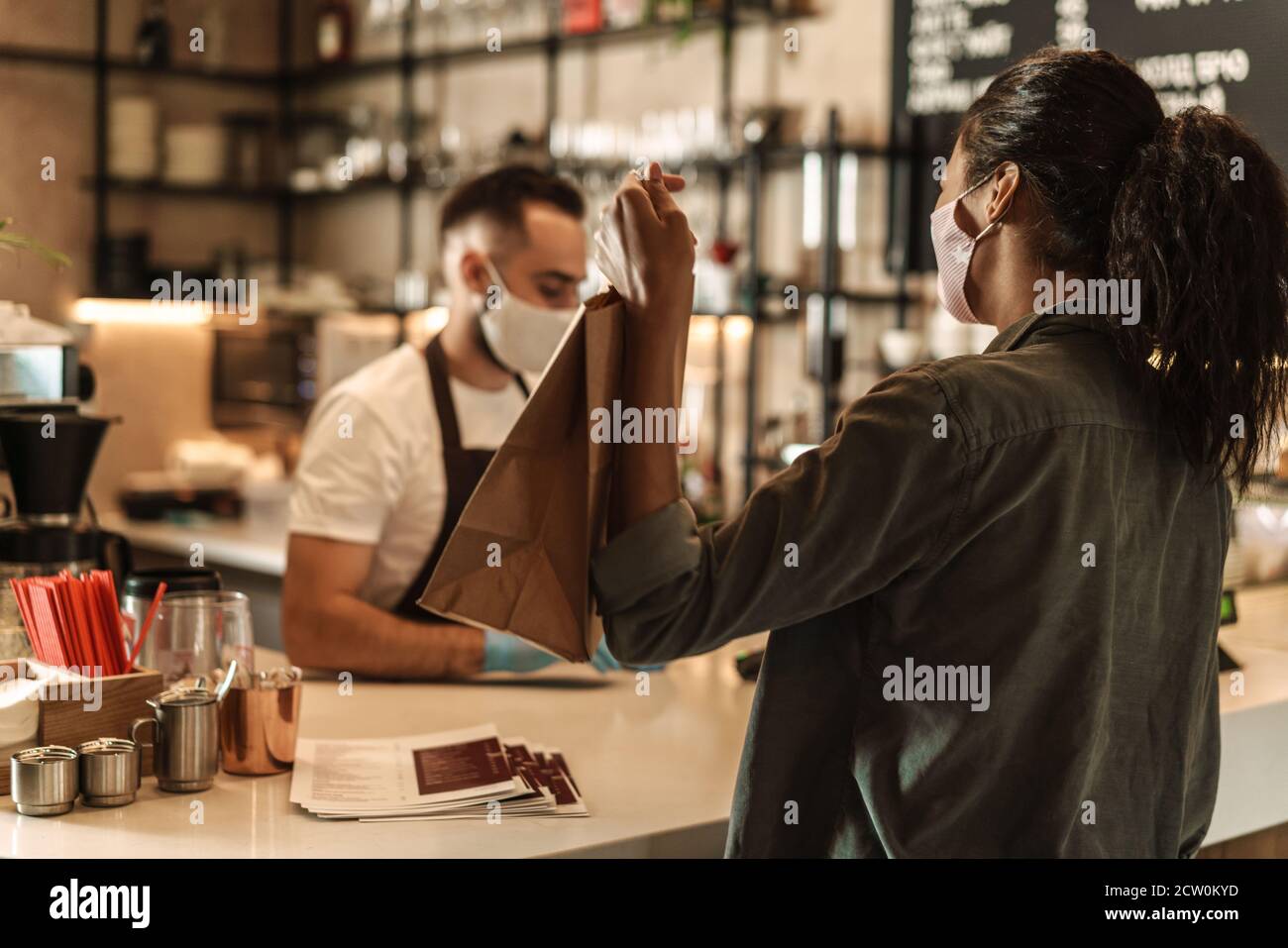 Customer paying and getting her order at the coffee shop counter during ...