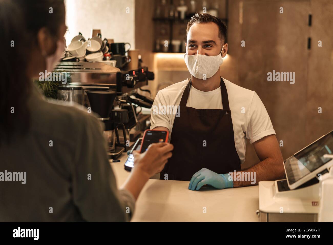 Customer paying and getting her order at the coffee shop counter during ...