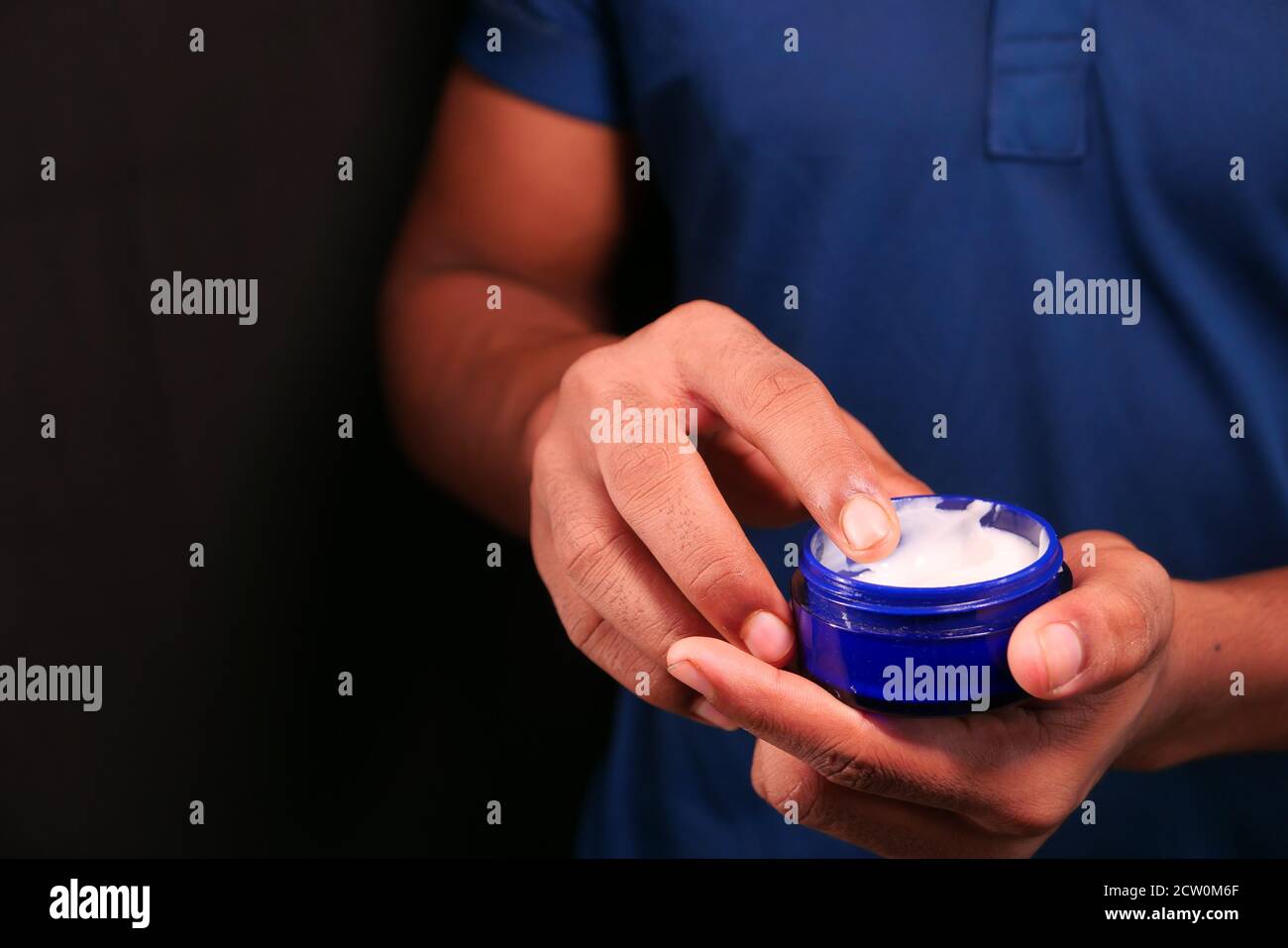 man applying beauty cream onto skin isolated in black Stock Photo - Alamy