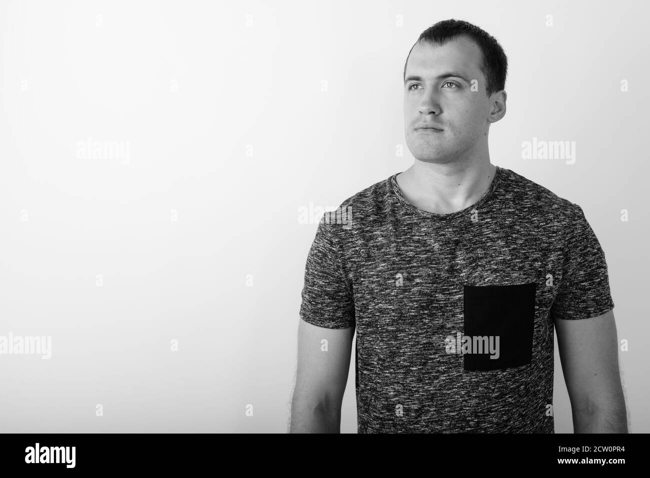 Studio shot of young muscular man thinking while looking up against ...