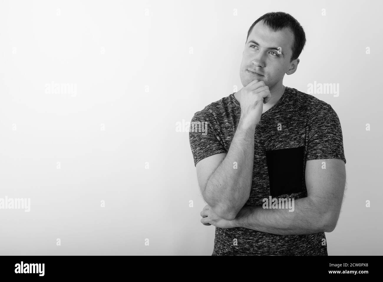 Studio shot of young muscular man thinking and looking up against white ...