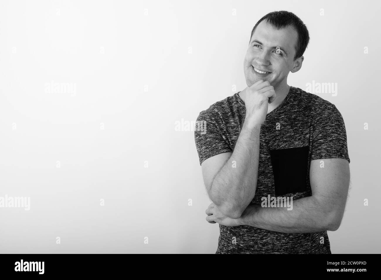 Studio shot of young happy muscular man smiling while thinking and ...