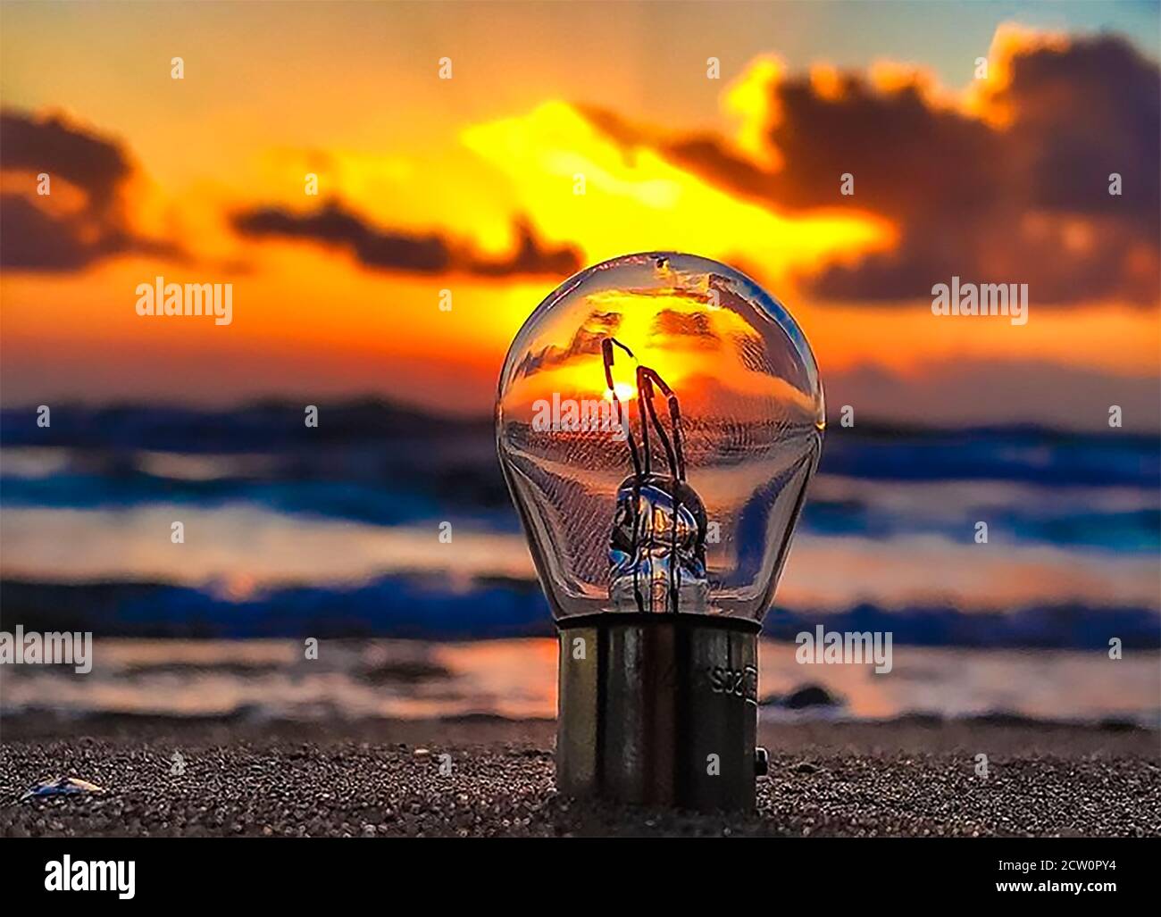 Sunset with a glowing lightbulb with the rays of the sun reflecting off ...