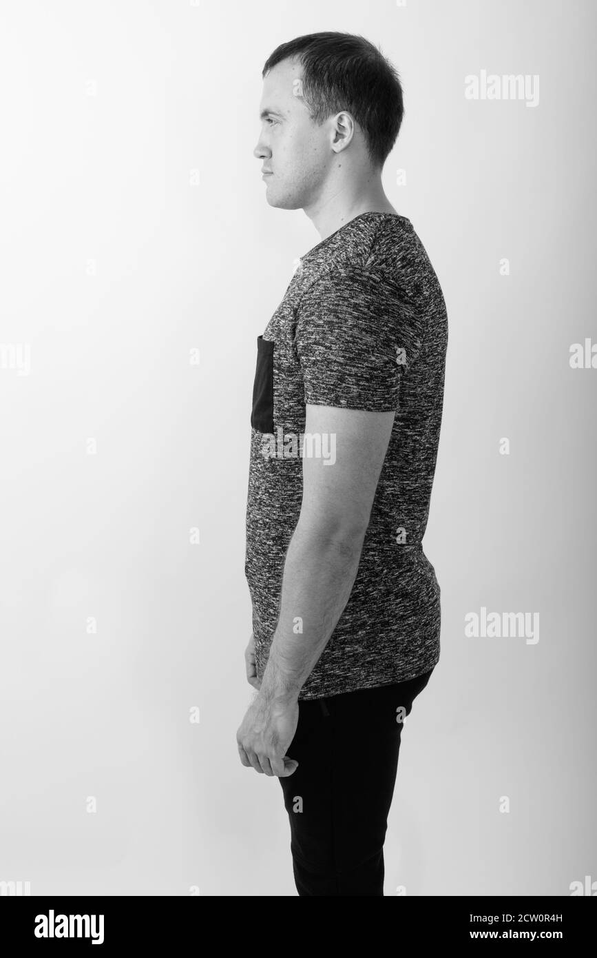 Profile view of young muscular man standing against white background ...