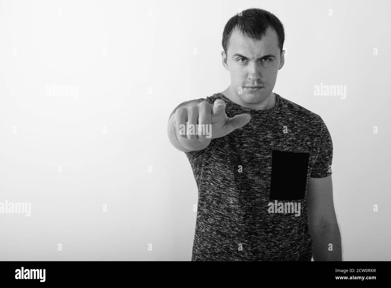 Studio shot of angry young muscular man pointing at camera against ...