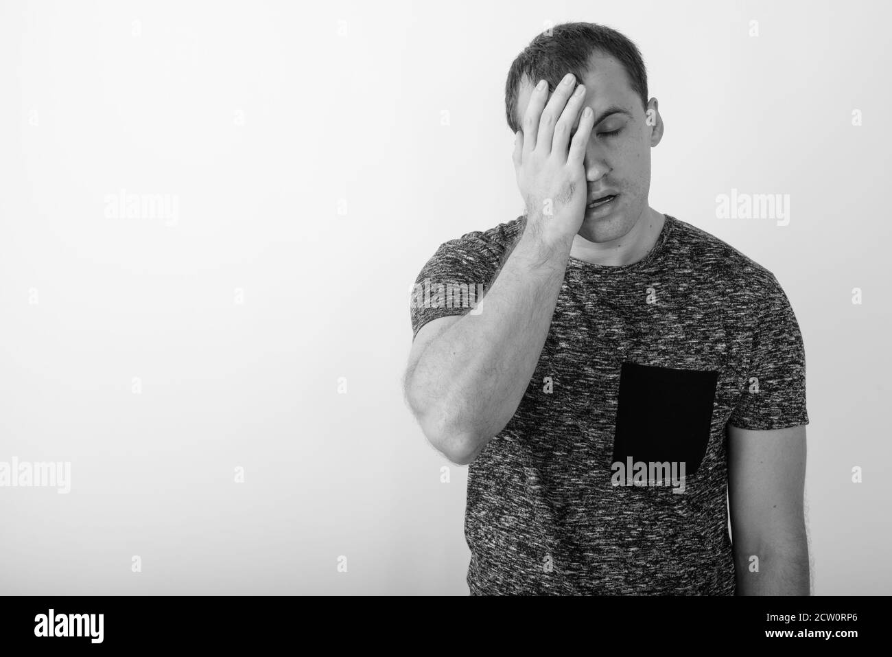 Studio shot of young muscular man looking tired while covering face ...