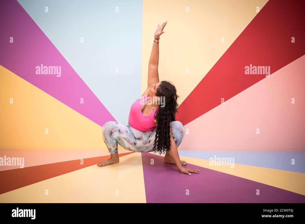 young woman in a yoga pose in a colorful room Stock Photo - Alamy