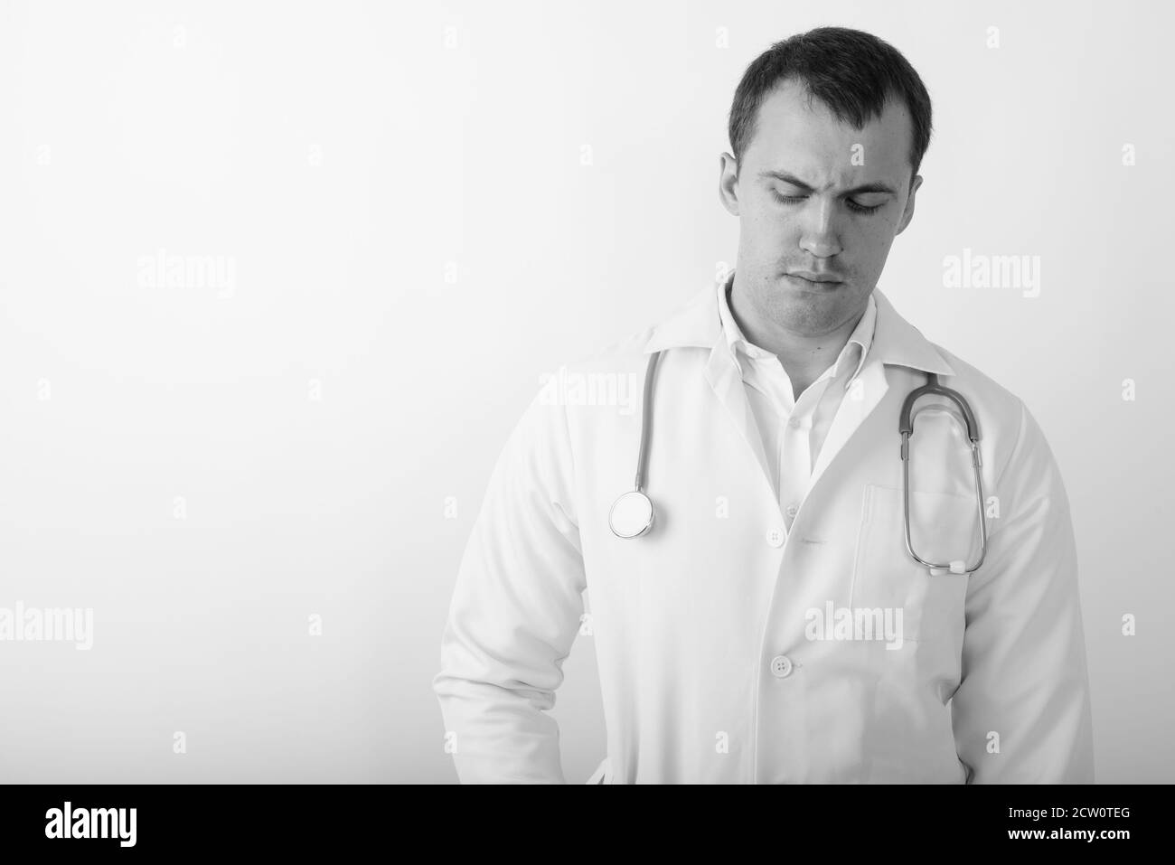 Studio shot of young muscular man doctor thinking while looking down ...