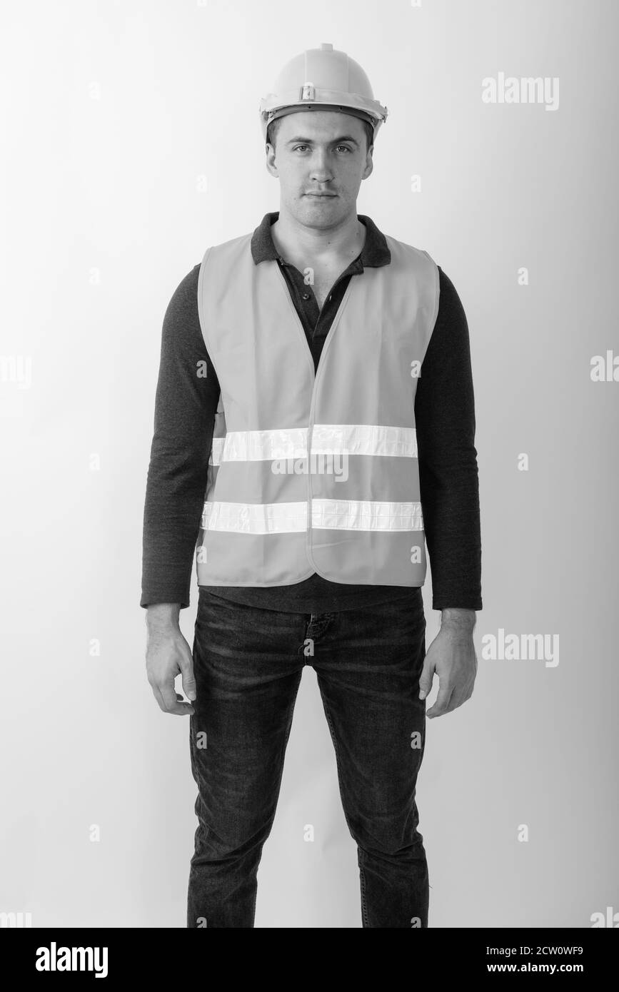 Studio shot of young muscular man construction worker standing against ...