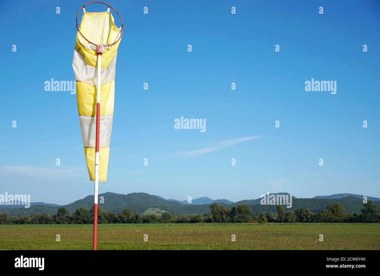 Yellow and white windsock placed in a large field during daylight Stock ...