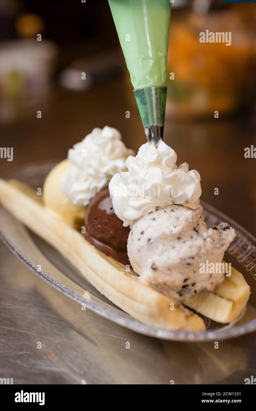 Preparation of artisanal Italian Banana split with ice cream, whipped ...