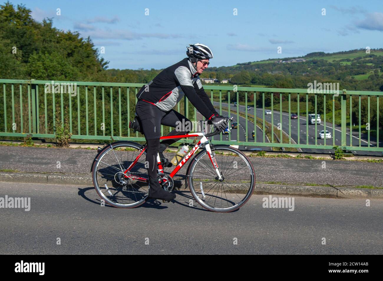 Male cyclist riding red white Trek road bike on countryside route ...
