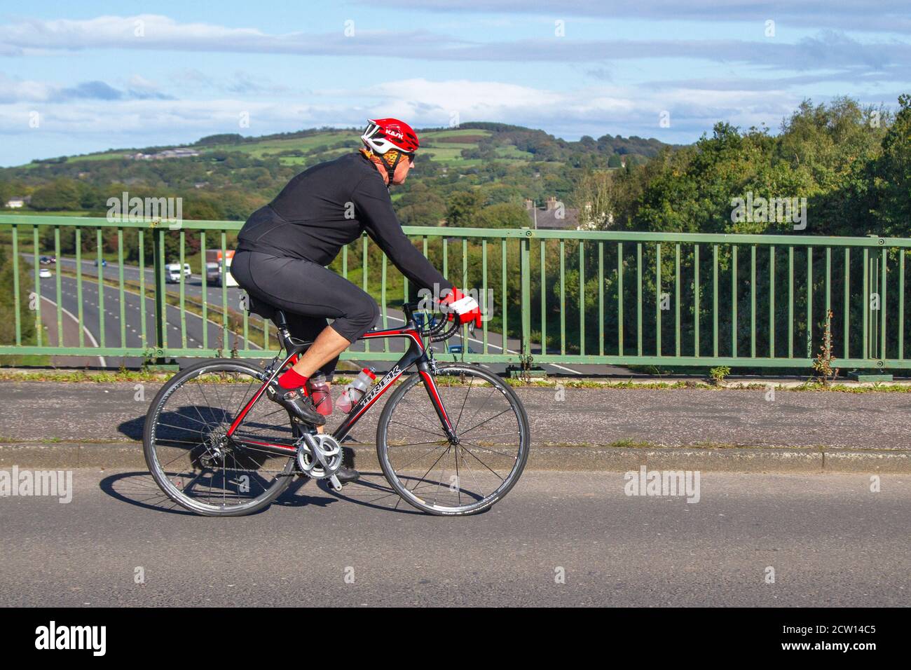 Male cyclist riding TREK road bike on countryside route crossing ...