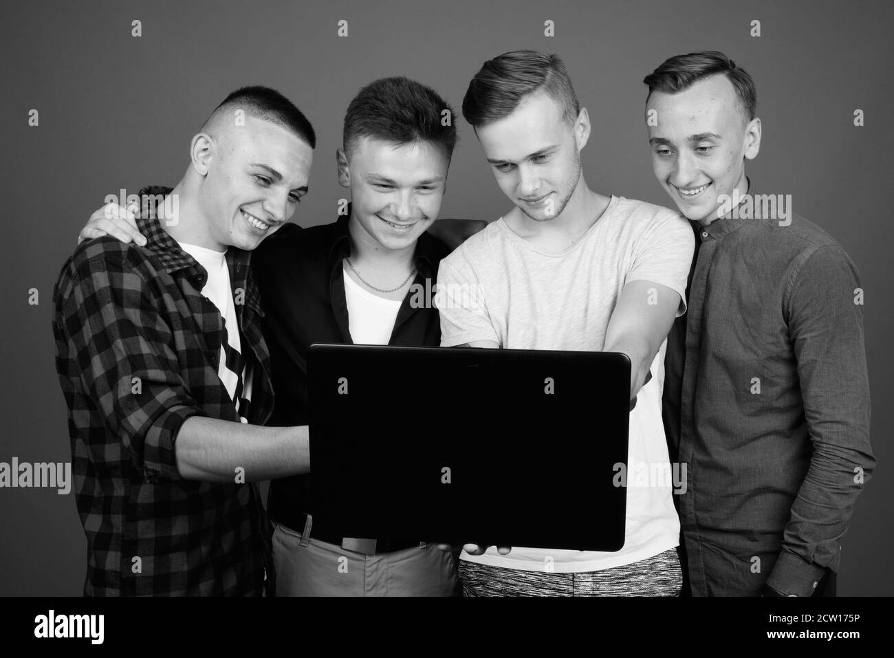 Four young handsome men together against gray background Stock Photo ...