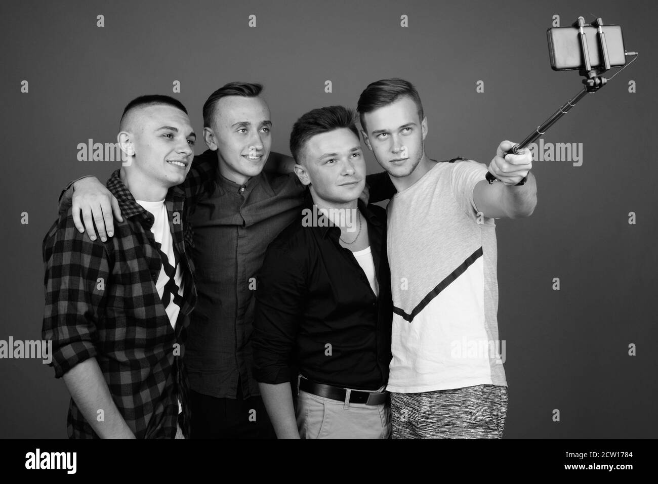 Four young handsome men together against gray background Stock Photo ...