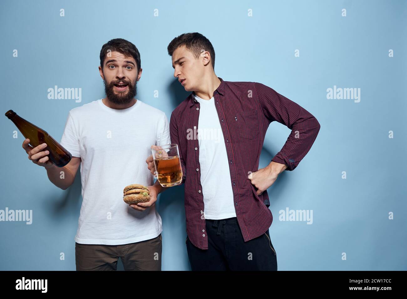 Two cheerful drunk friends drinking beer lifestyle emotions on a blue ...