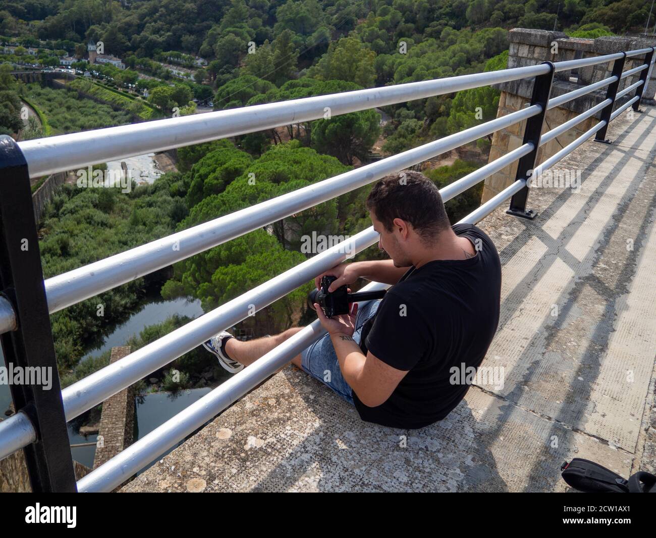Male photographer sitting on a bridge Stock Photo - Alamy
